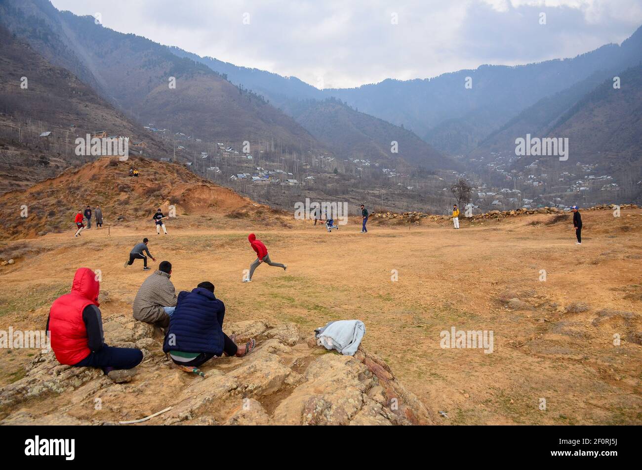 Kashmiri boys play cricket on the hill during a cloudy day on the ...
