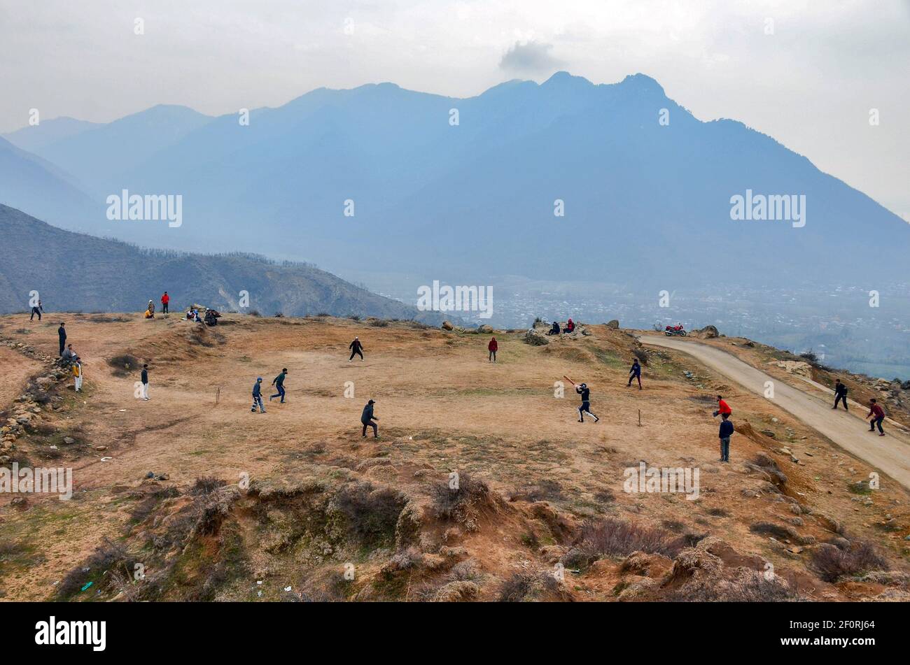 Kashmiri boys play cricket on the hill during a cloudy day on the ...
