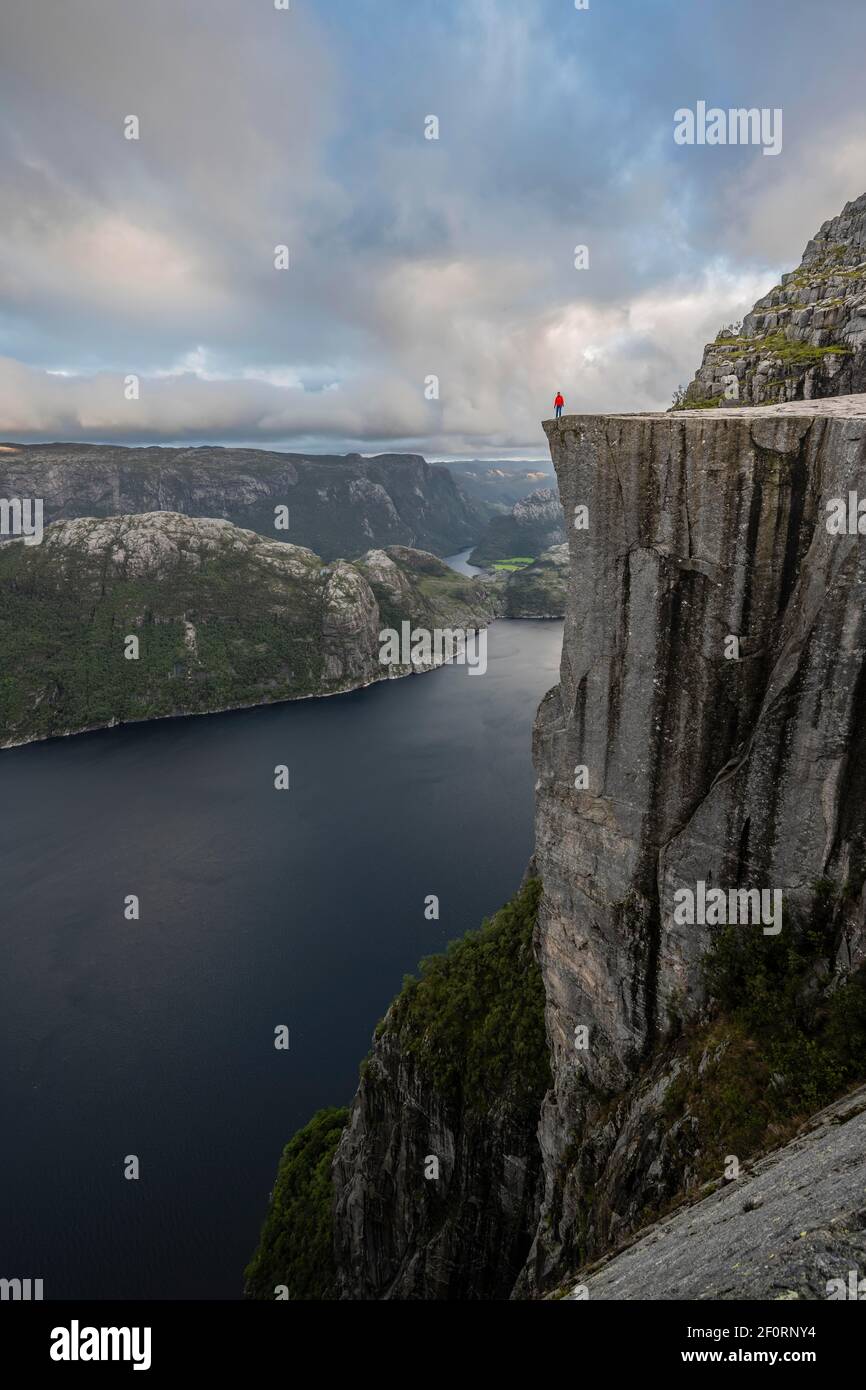 Person standing on steep cliff, Preikestolen rock spire, Lysefjord ...