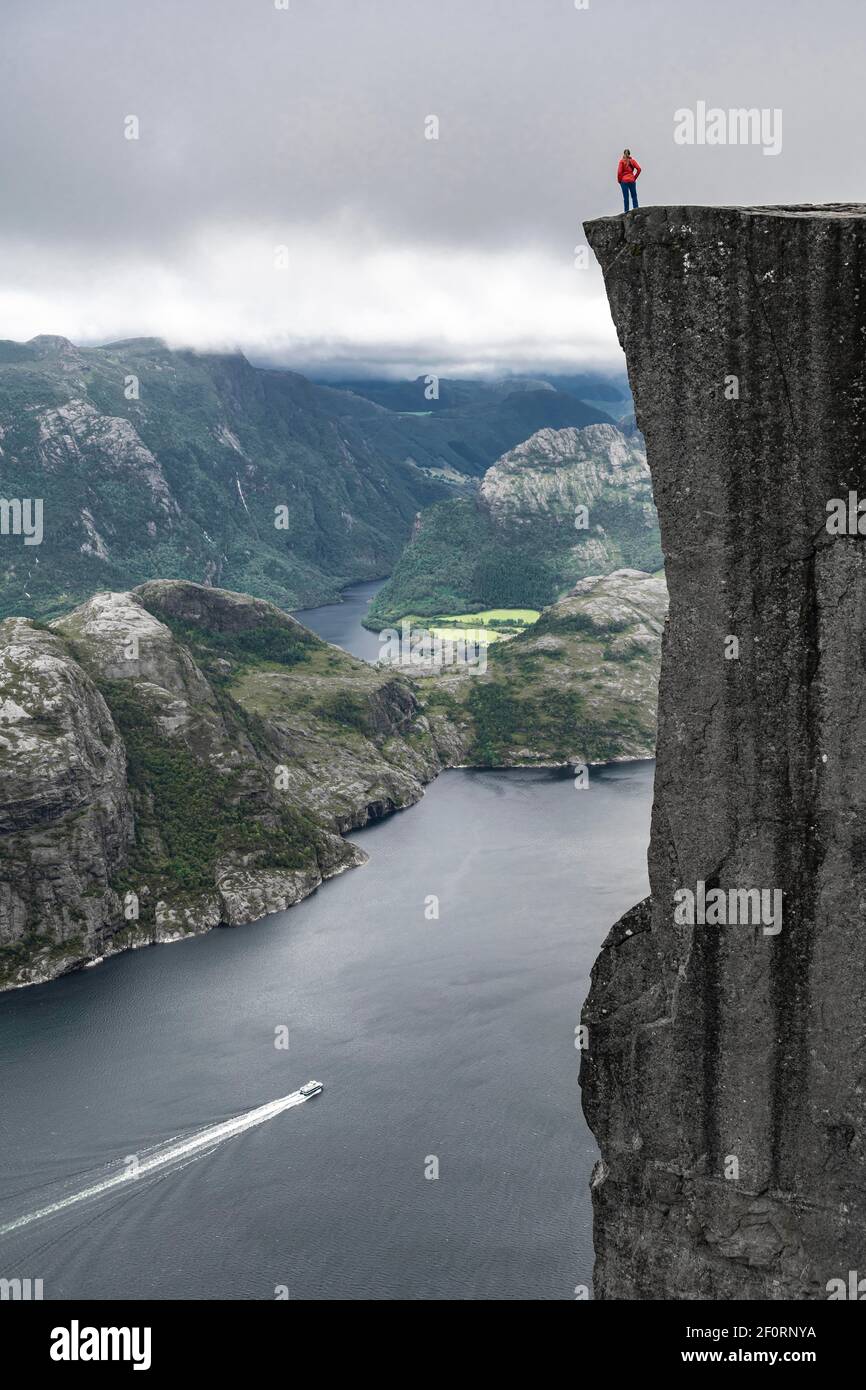 Person standing on steep cliff, Preikestolen rock spire, Lysefjord ...