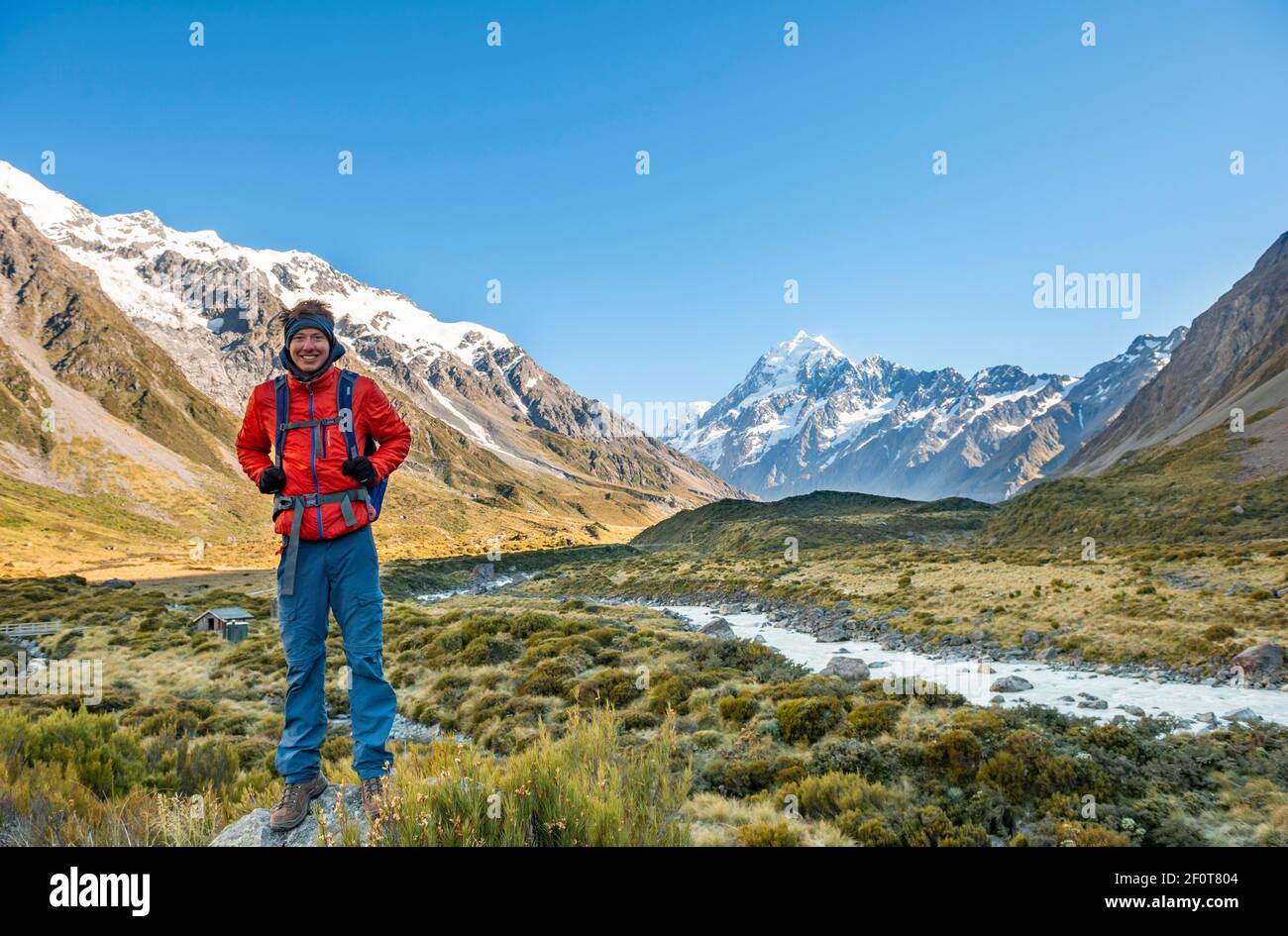 Hiker standing on a rock, Hooker Valley overlooking snow-capped Mount ...