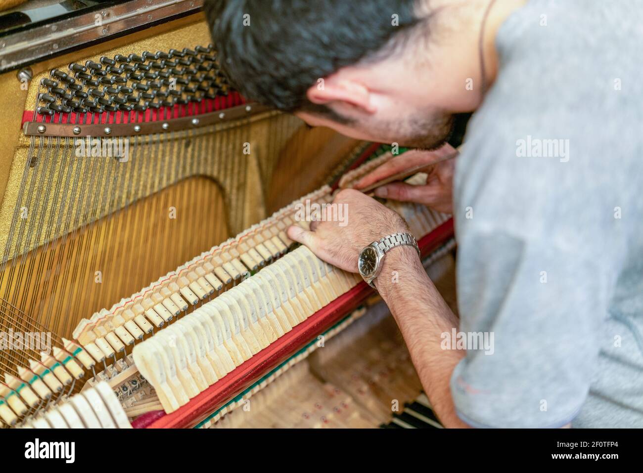 Piano tuning process. closeup of hand and tools of tuner working on ...