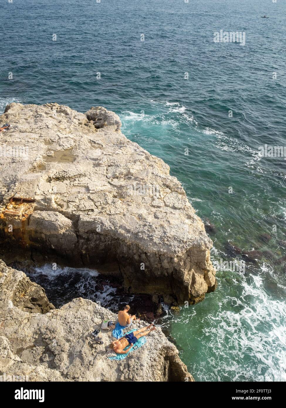 Sunbathing on the rocks by the Mediterranean Sea in Siracusa Stock ...