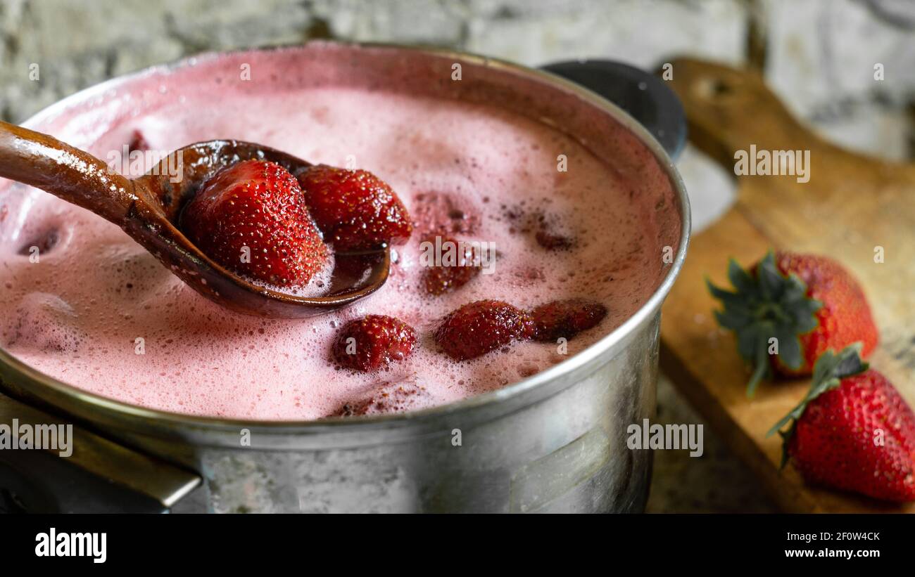 Cooking strawberry jam. Berries with sugar boiling in a pan forming a ...