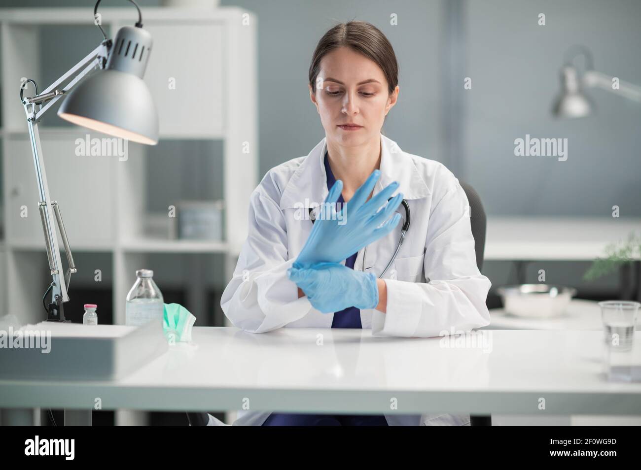 A young female internist is sitting at a desk in her spacious, bright ...