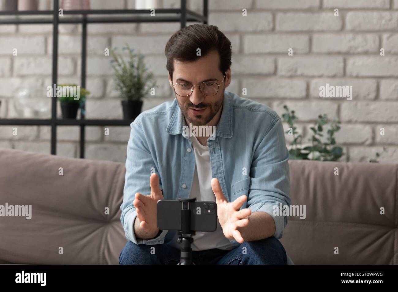 Confident male coach sit on sofa before smartphone record training ...