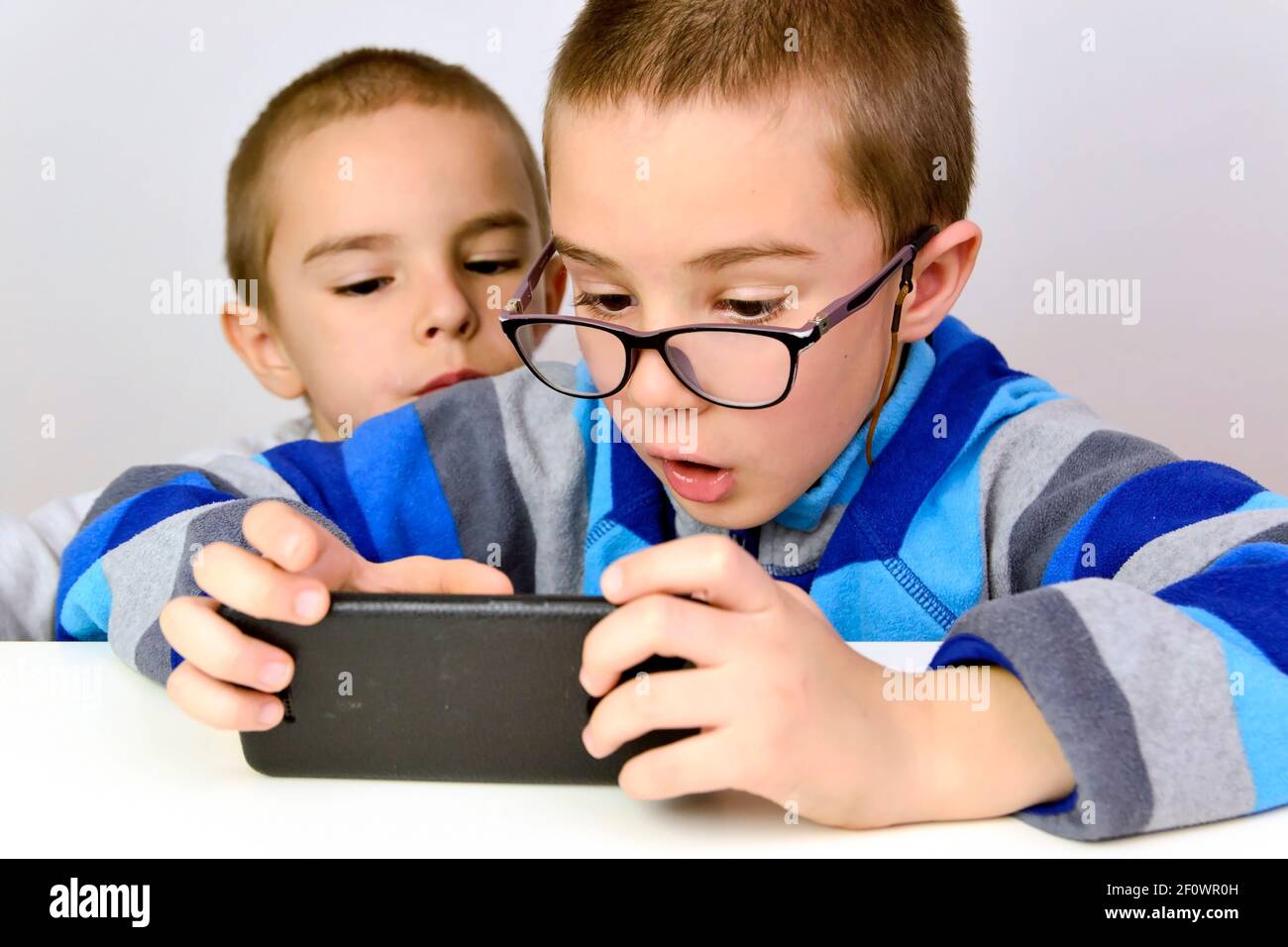 Two little boys playing a game on the smartphone Stock Photo - Alamy