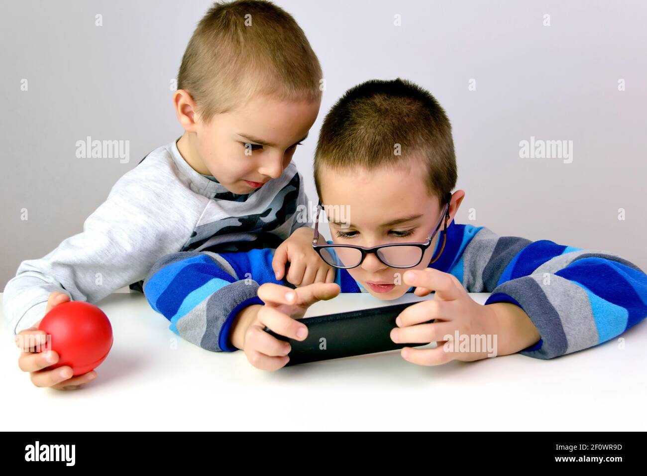 Two little boys playing a game on the smartphone Stock Photo - Alamy