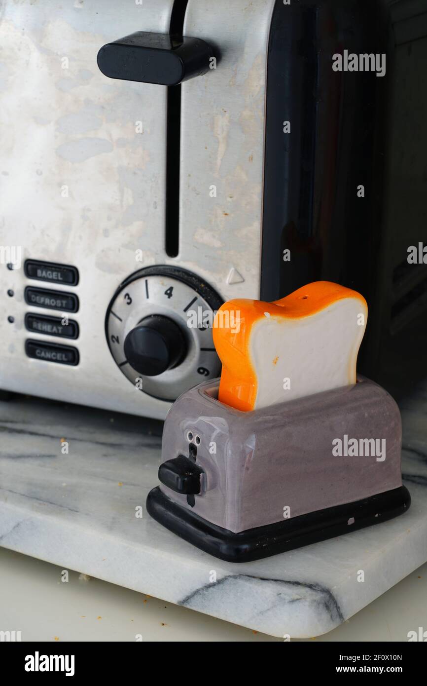 A steel and black toaster with a miniature ceramic toaster Stock Photo ...