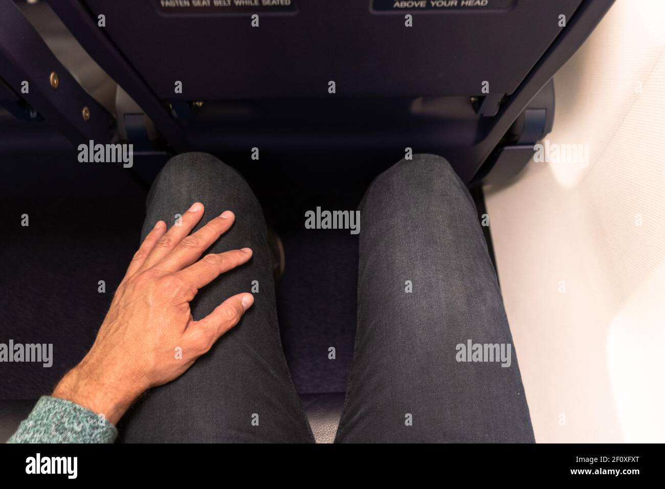 Top view of a man with a hand over his leg and the legroom in the ...