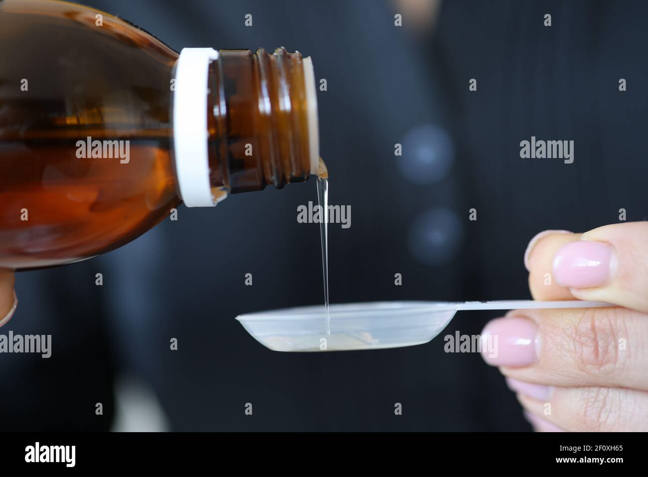 Woman's hand pours cold syrup into spoon Stock Photo - Alamy