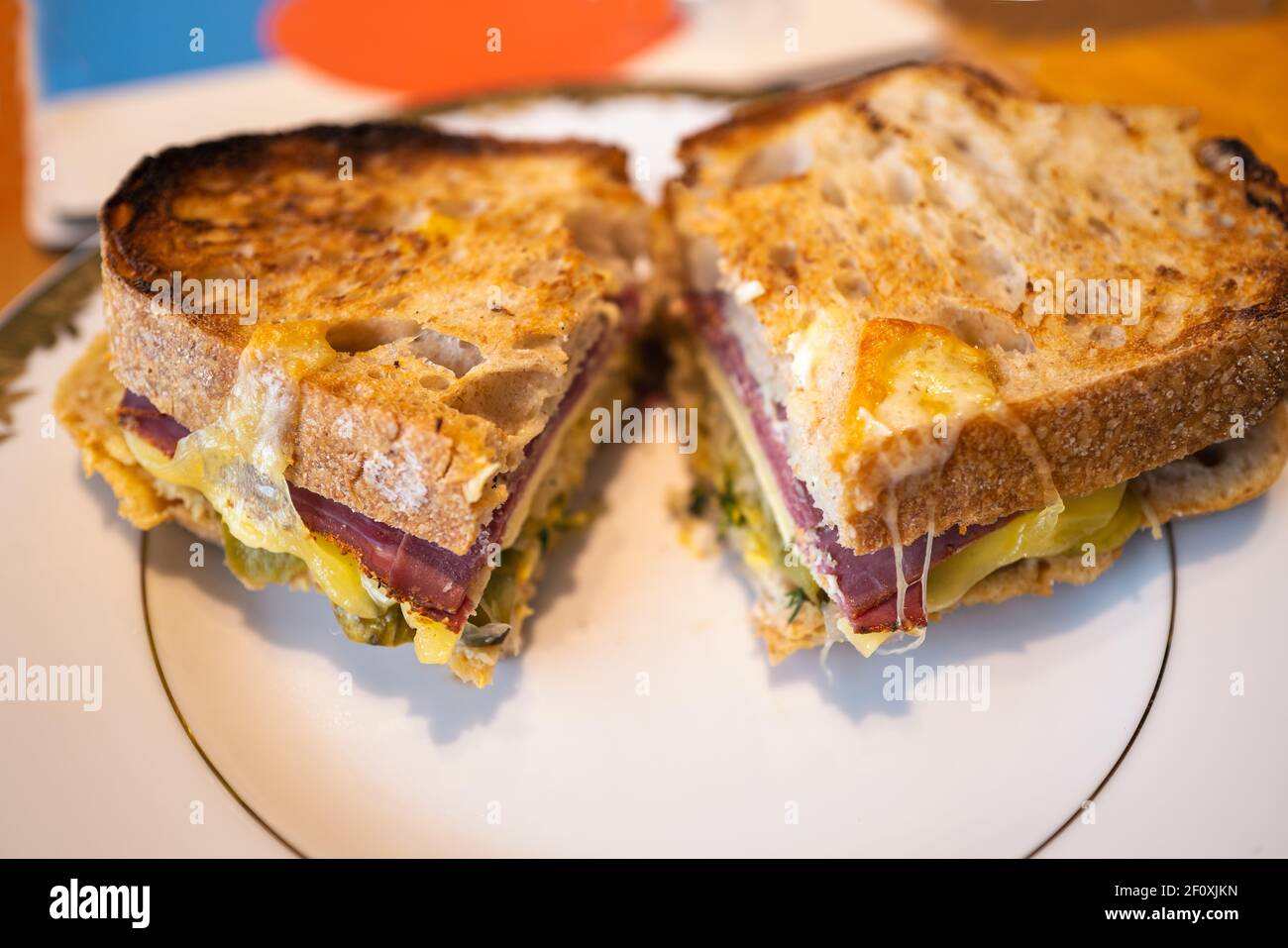 Toasted salt beef cut sandwich with melted cheese and pickle on a white ...