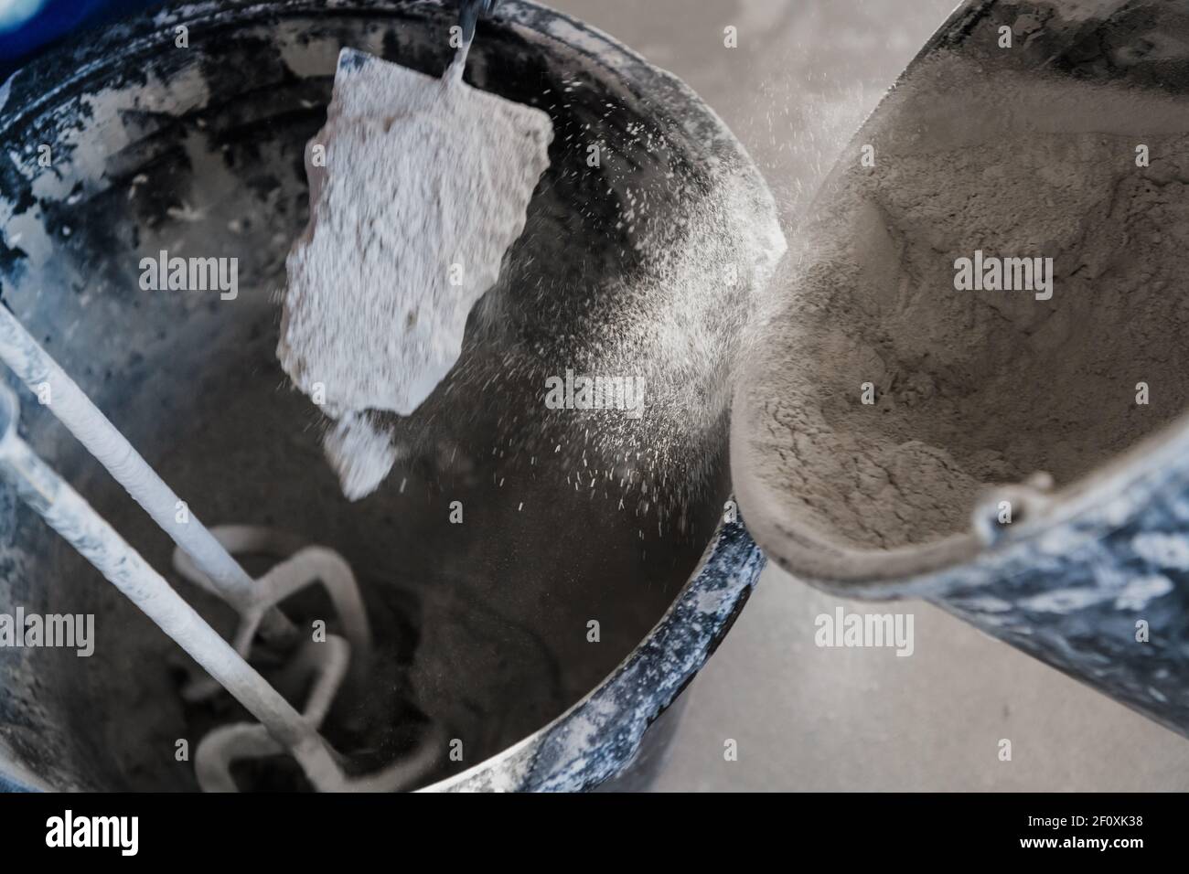 Builders put dry plaster into a bucket with a spatula Stock Photo - Alamy