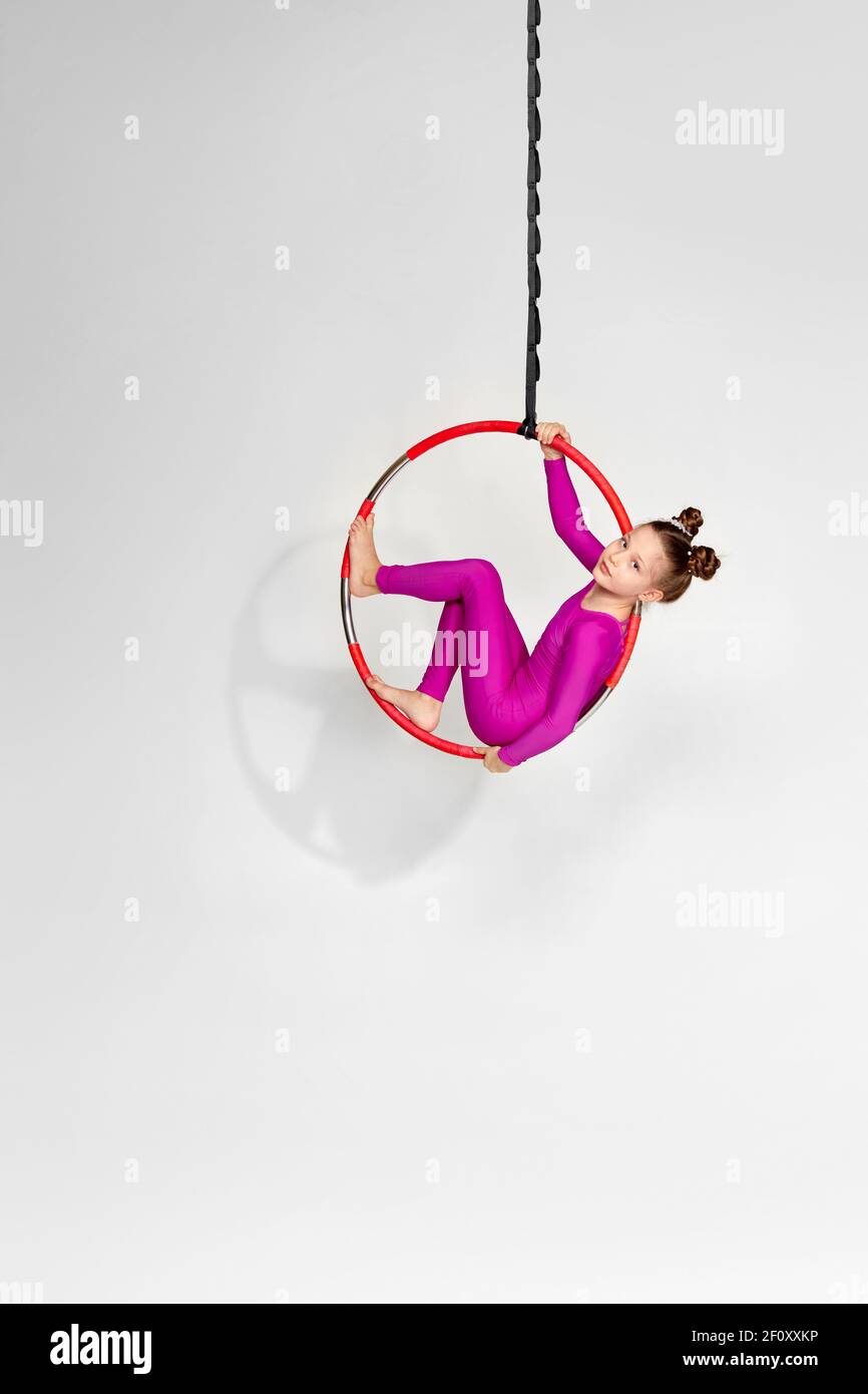 little child girl gymnast in pink sportwear shows an acrobatic ...