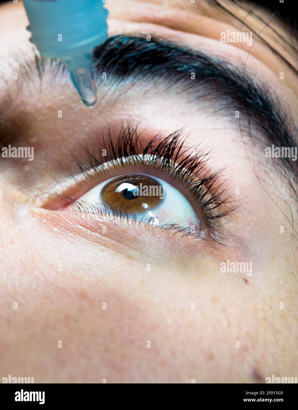 Detail photography of a caucasian man applying eyedrops in his brown ...