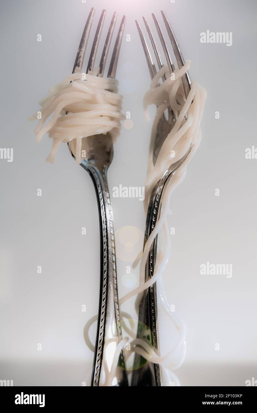 two forks vertically placed in which spaghetti intertwined. Him and her ...