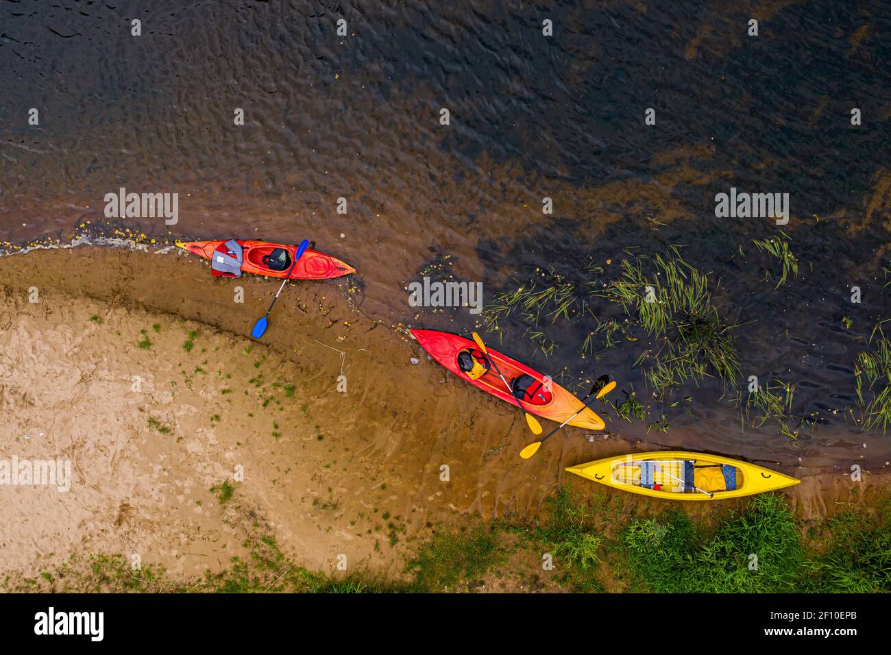 multicolored empty kayaks and canoes on the river bank, top down view ...