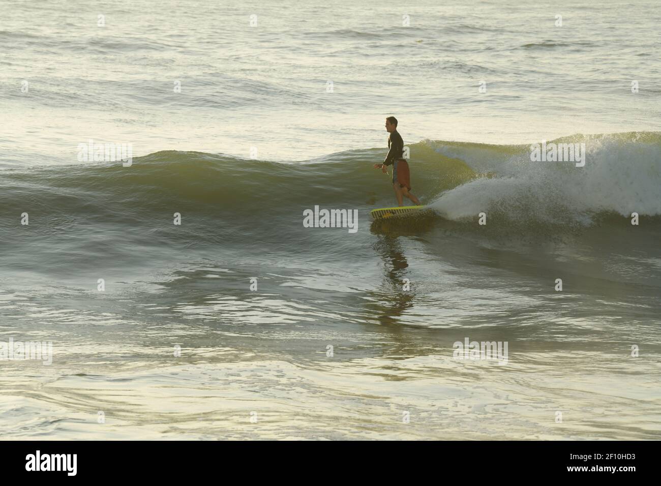 Surfing, active lifestyle, young adult man, surfer on surfboard riding ...