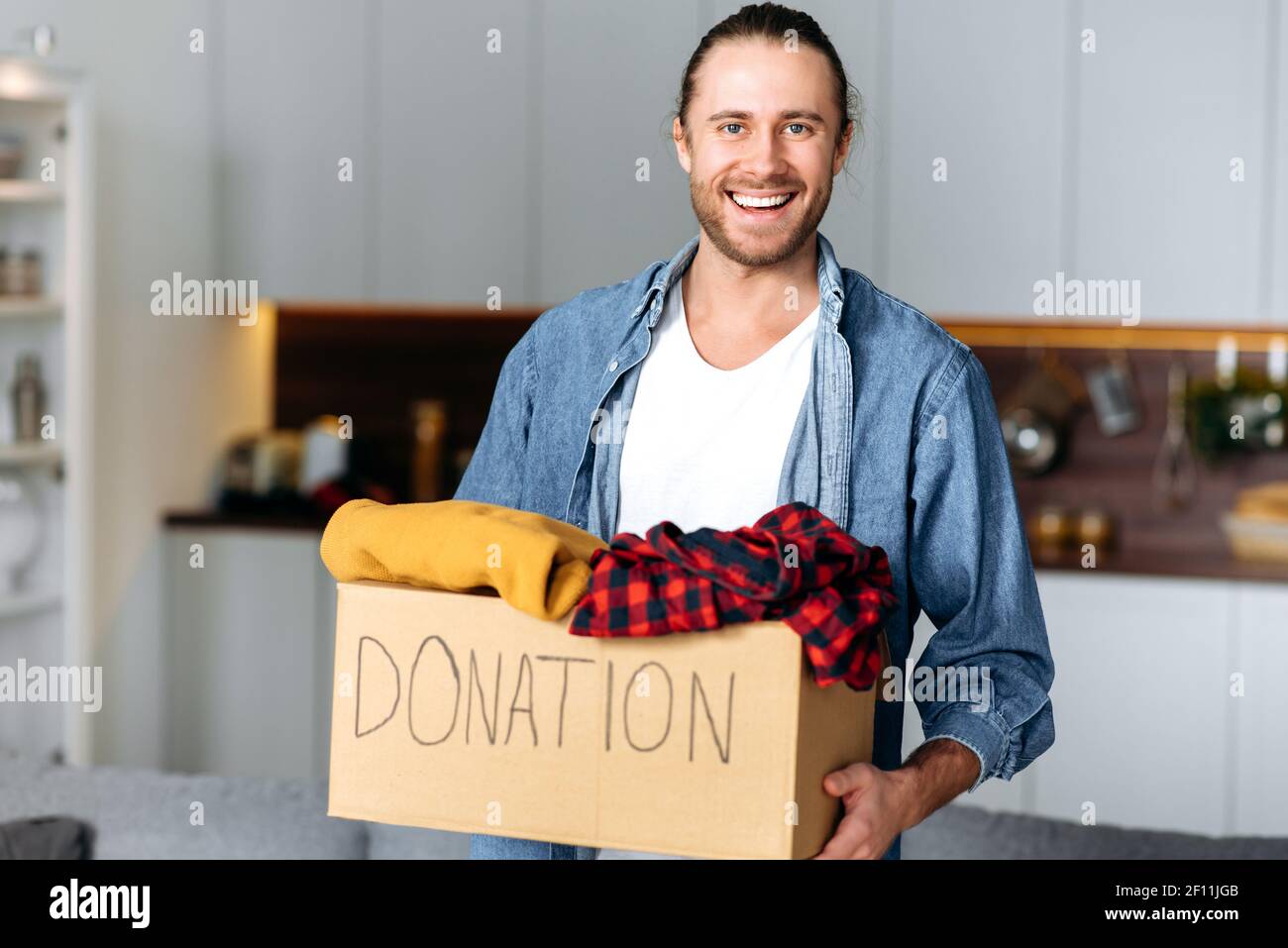 A smiling candid caucasian male volunteer holds a cardboard box with a ...