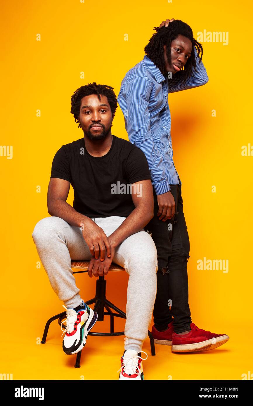 two african american guys posing cheerful together on yellow background ...