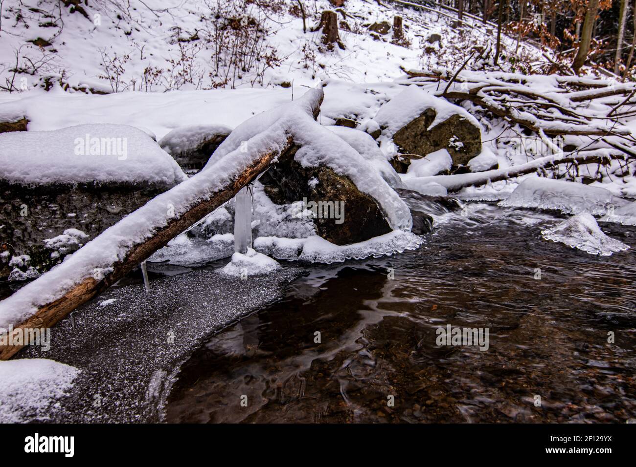 Icy wood log and rocks covered in snow in winter freezing river Stock ...