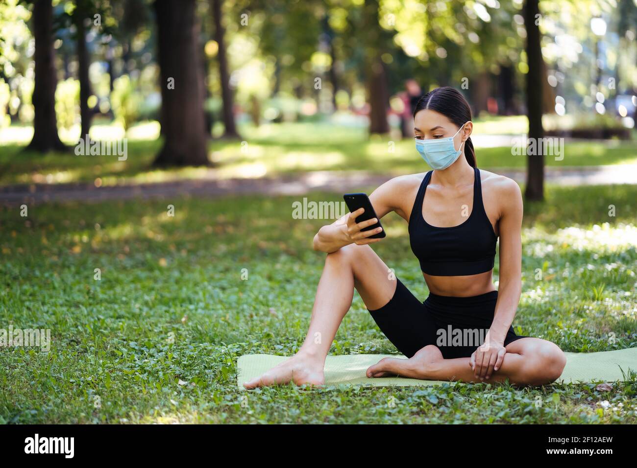 Fitness girl with a smartphone on nature background Stock Photo - Alamy