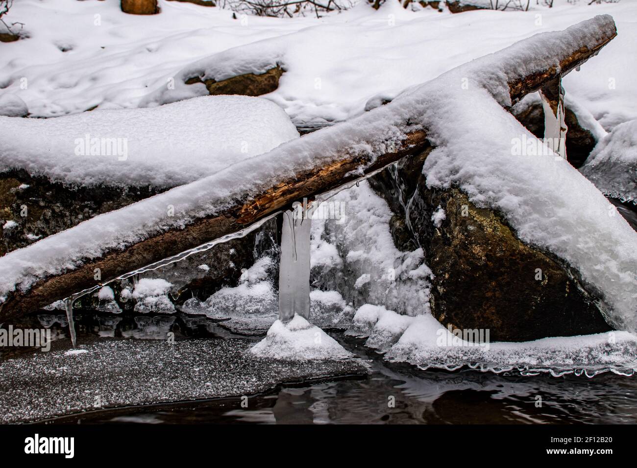 Icy wood log and rocks covered in snow in winter freezing river Stock ...