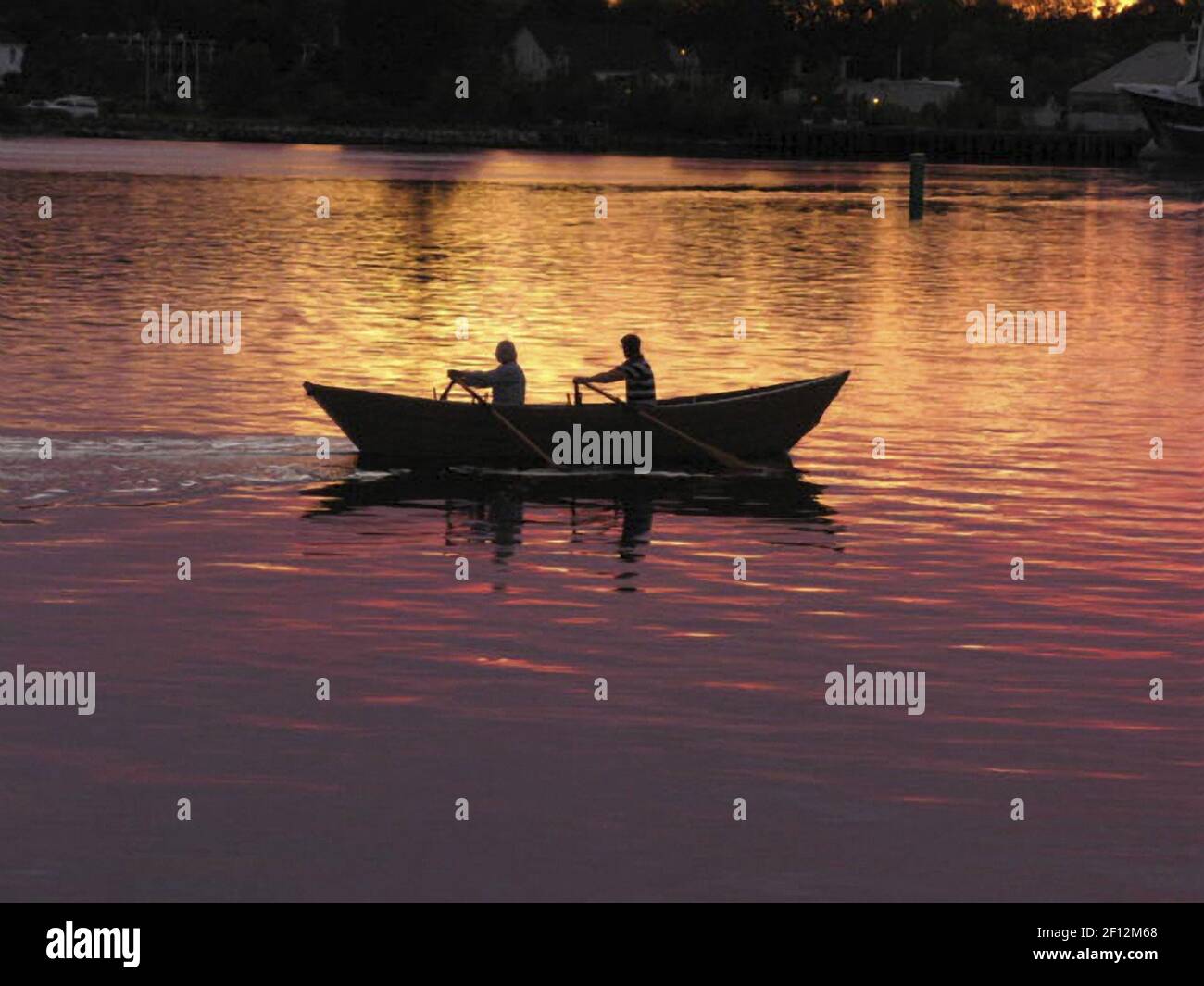 A dory cuts a silhouette across the harbor in Lunenburg, Nova Scotia ...
