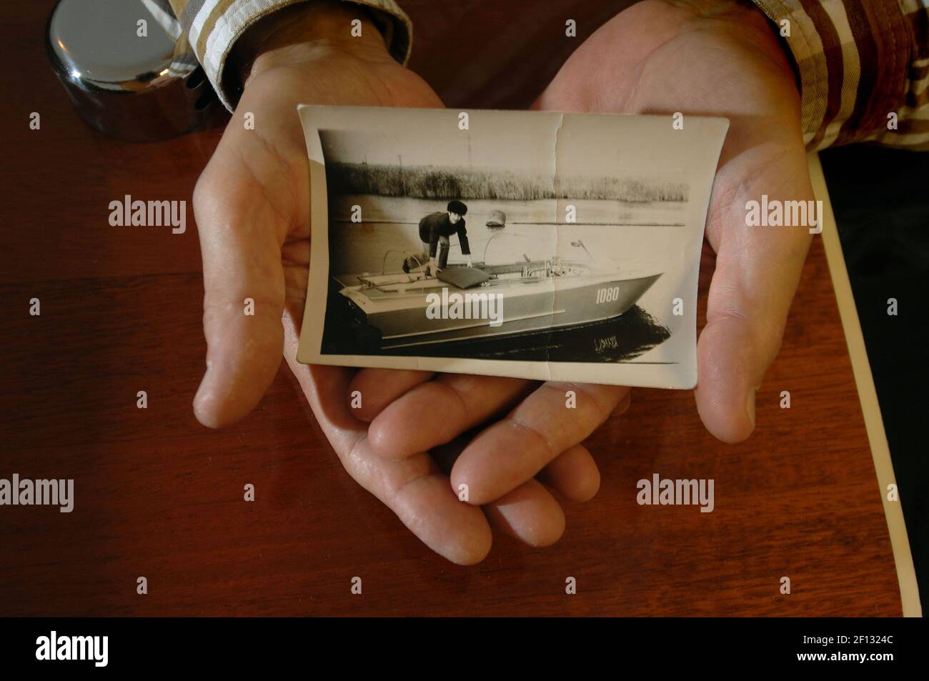 Alex Neymark holds a photograph of the boat he helped his father build ...