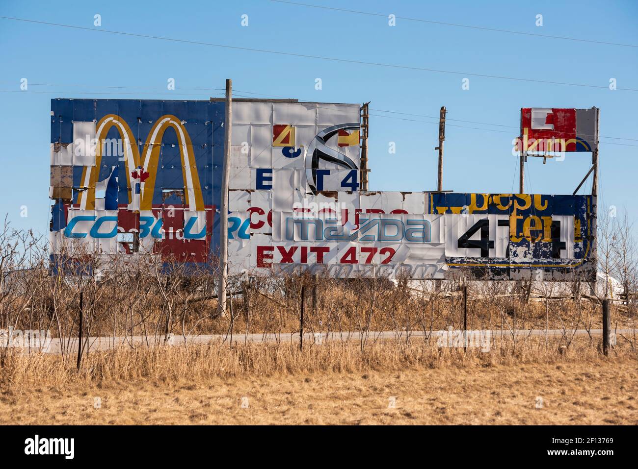 A tattered and weather-beaten billboard sign showing evidence of ...
