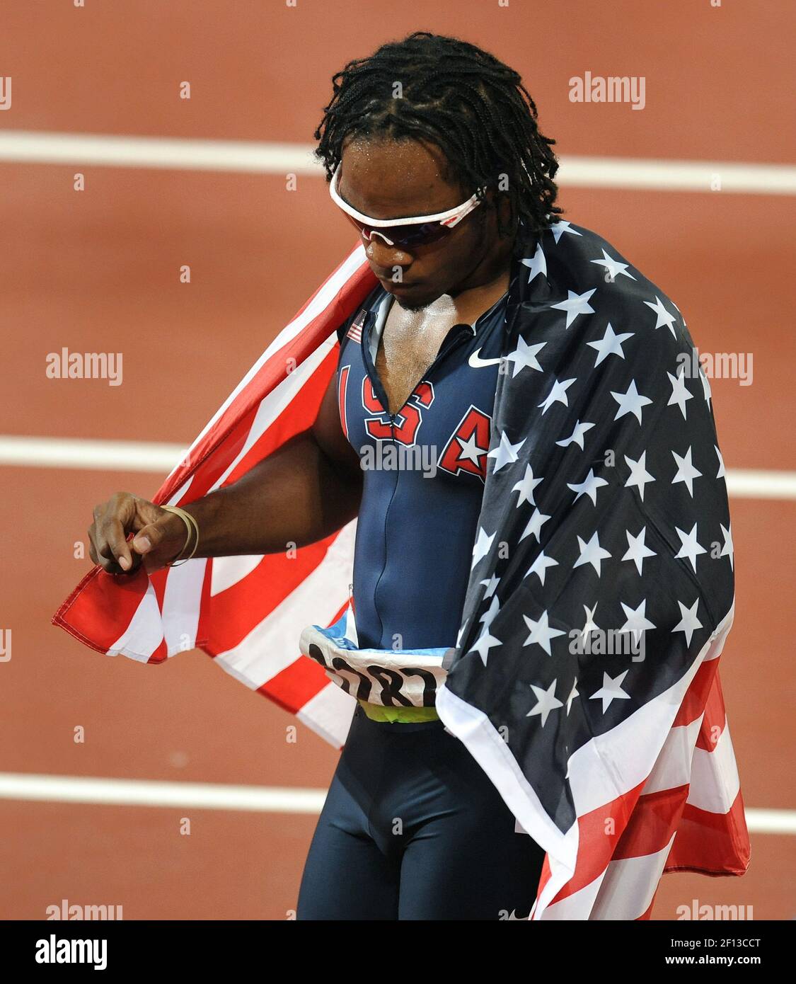 Walter Dix of the United States carries the flag after a silver-medal ...