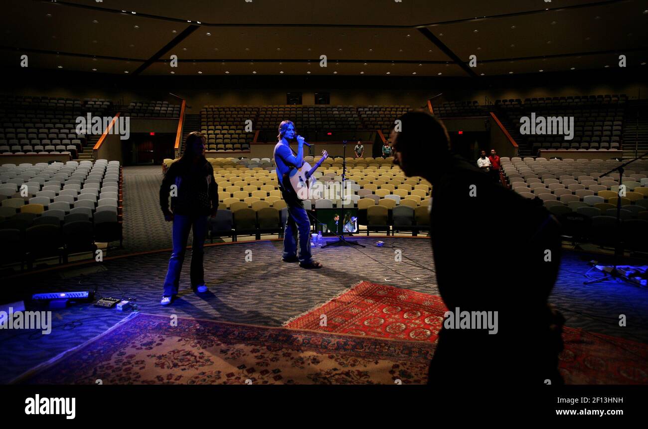 Members of the worship team and stage crew set up the stage, sound, and ...