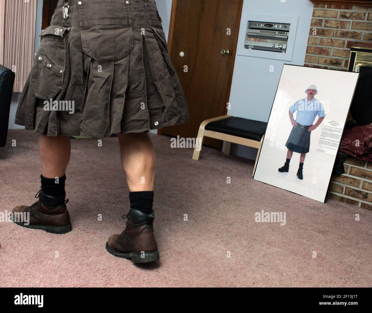 Dean Peterson walks past a poster he made of himself modeling a ...