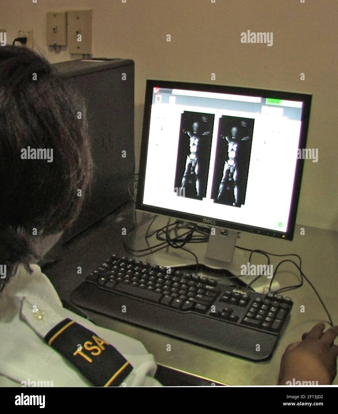 A TSA screener observes an image from a new whole-body scanner ...