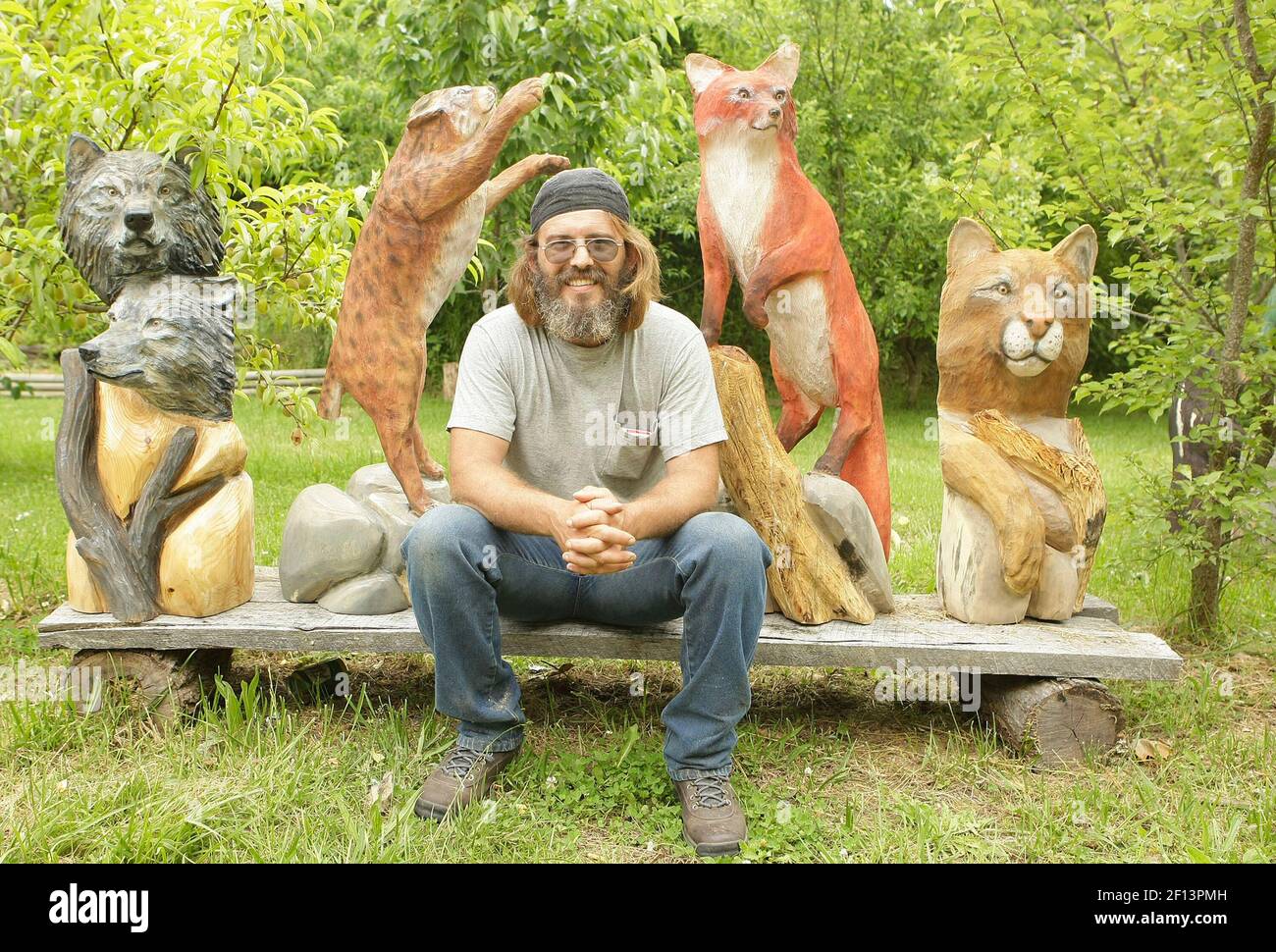 Chainsaw artist Harley Dougherty sits with some of his chainsaw carving ...