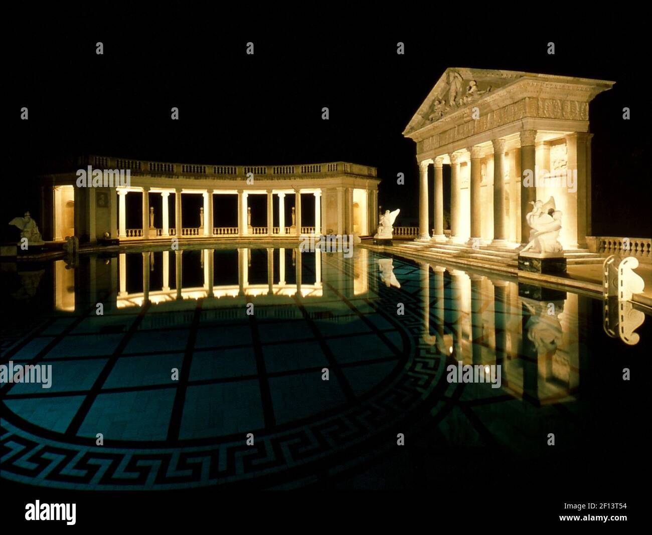 The Neptune pool is lit at night, accentuating the Greek columns and ...