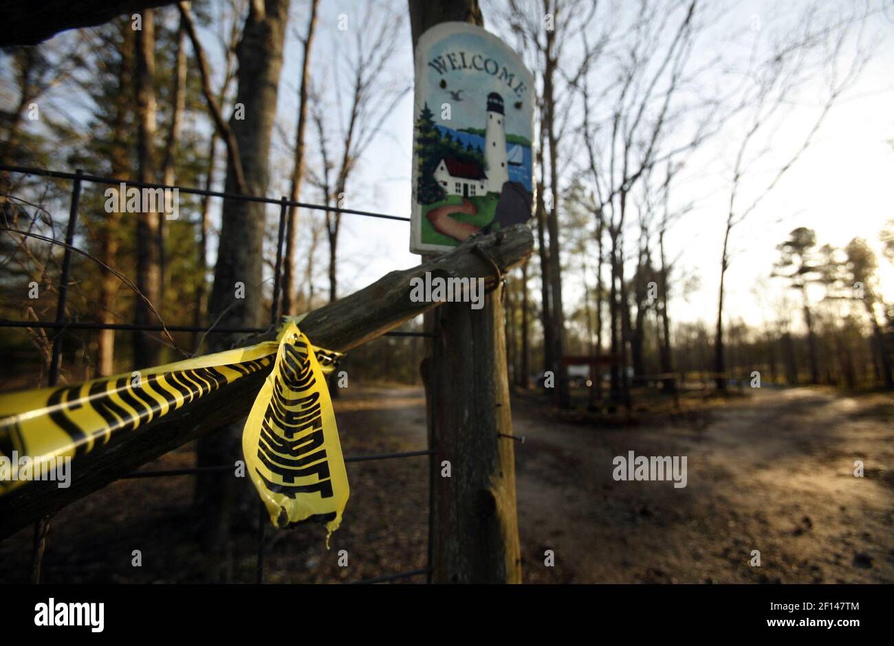 Crime scene tape and a welcome sign are seen at the front driveway ...