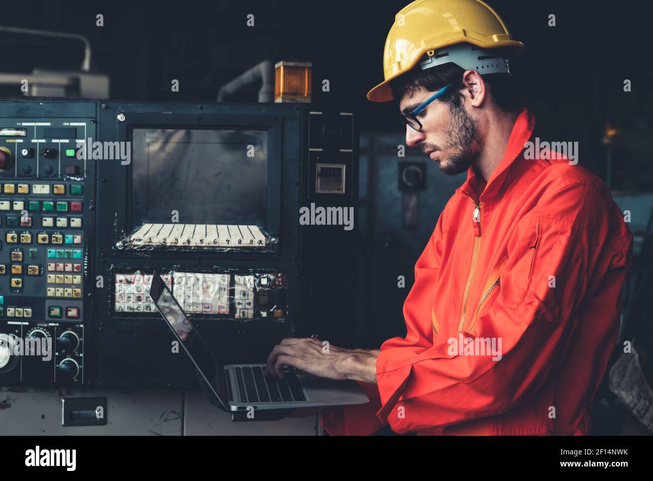 Skillful factory worker working with laptop computer to do procedure ...
