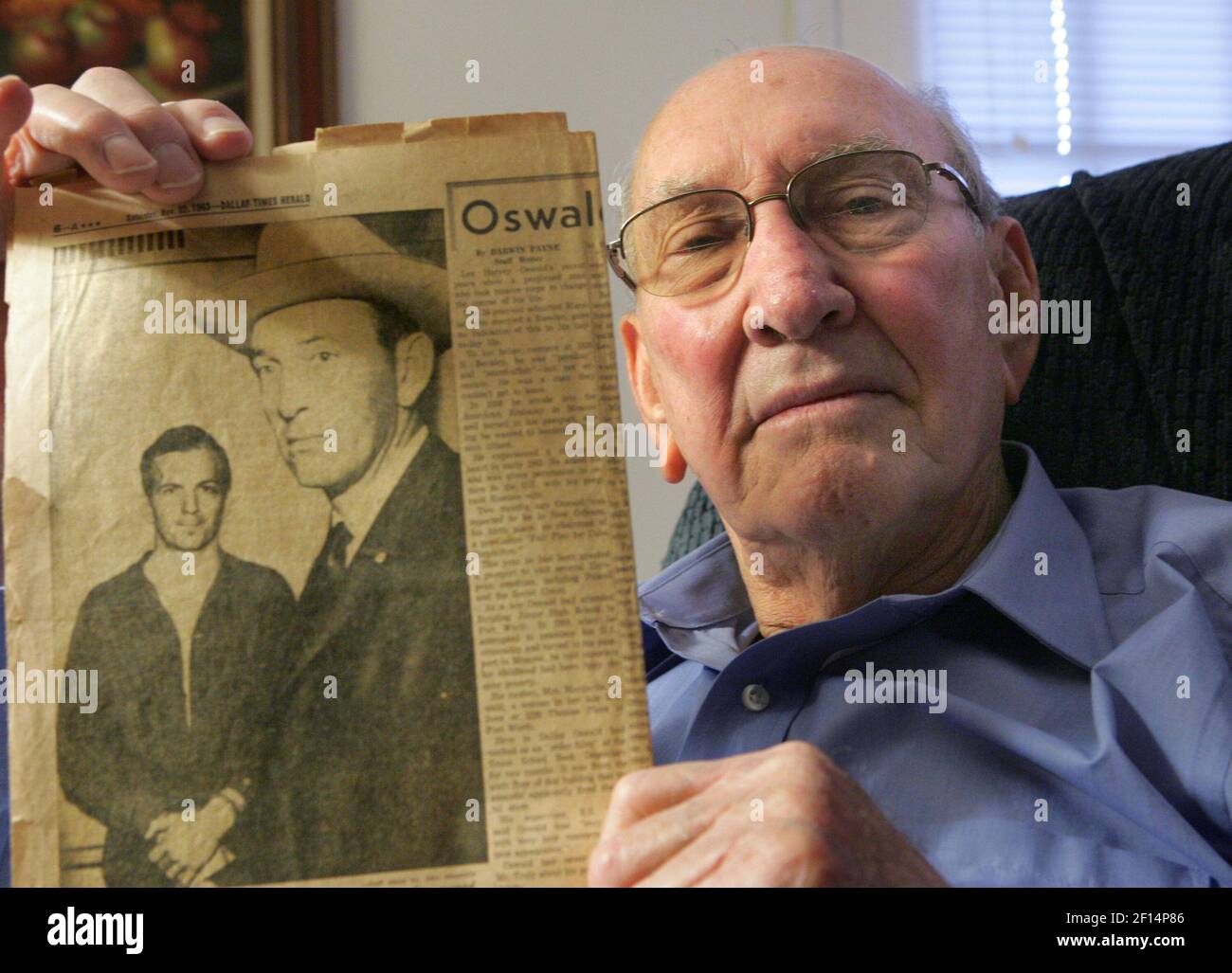 Richard Sims holds a yellowed page of newsprint showing a photograph of ...
