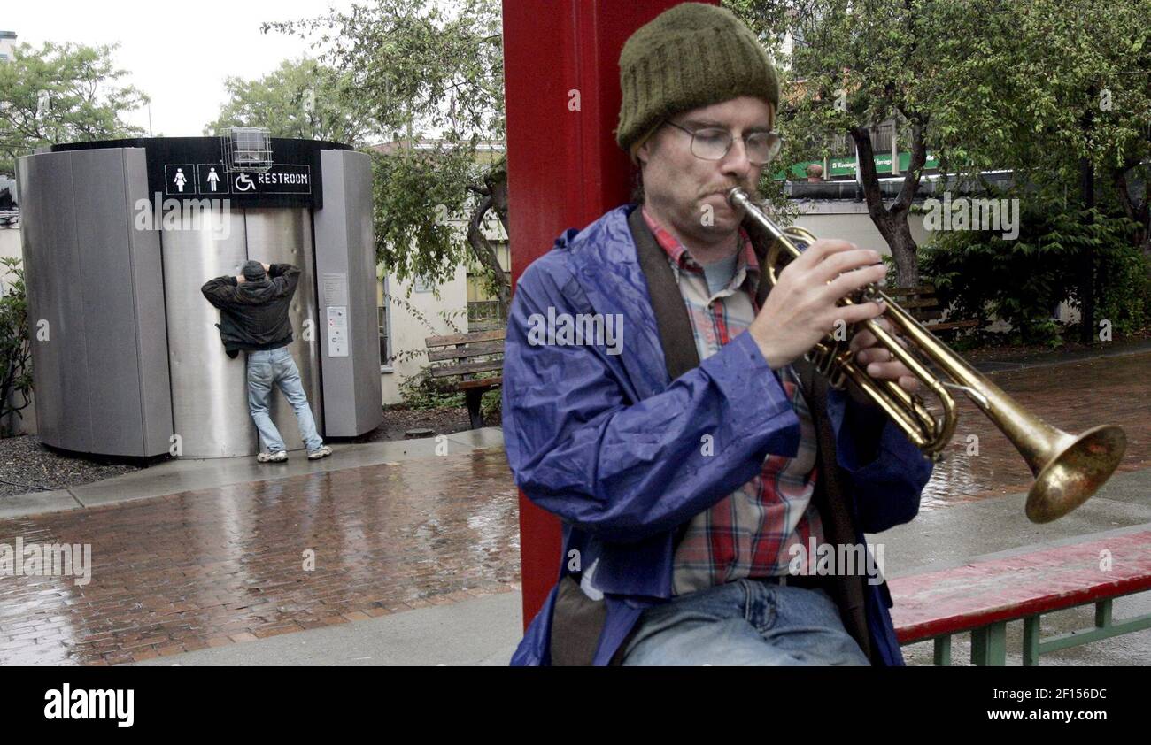 Busker Greg Spence Wolf performs in front of a public toilet that doors ...