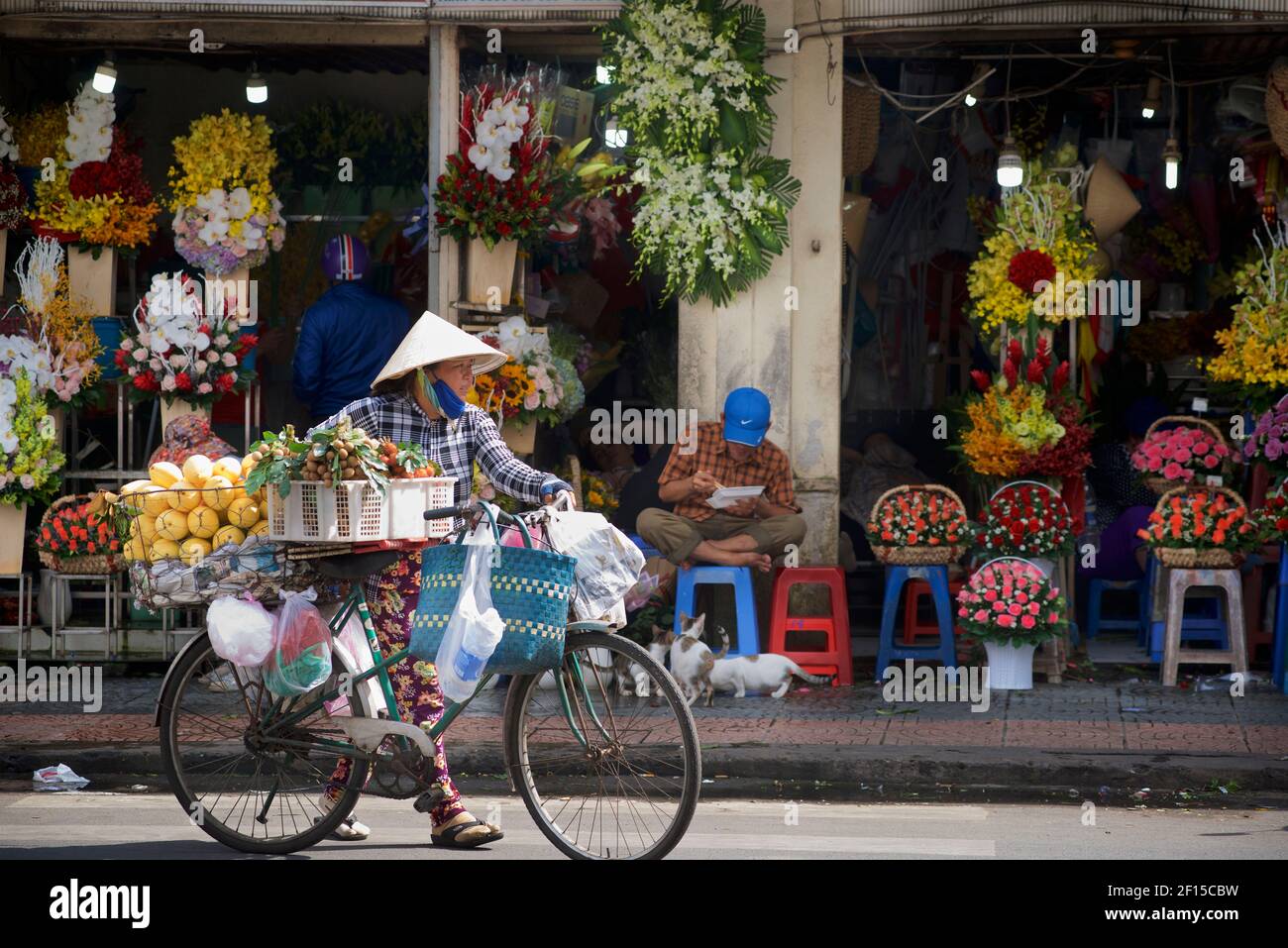 Fruit seller pushing her mobile bicycle stall alongside the flower ...