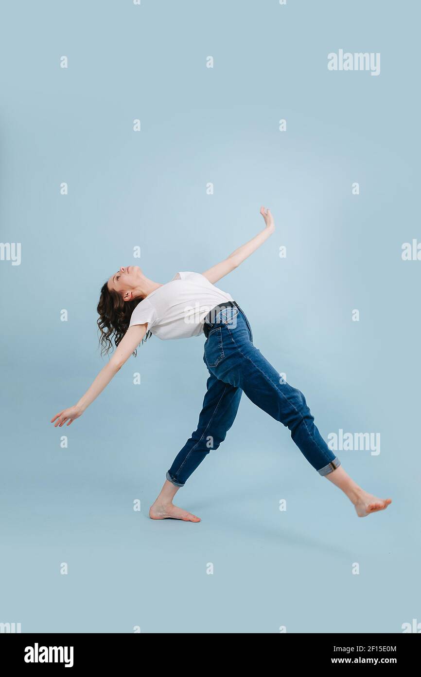 Flexible graceful contemporary dancer poses in front of blue studio ...