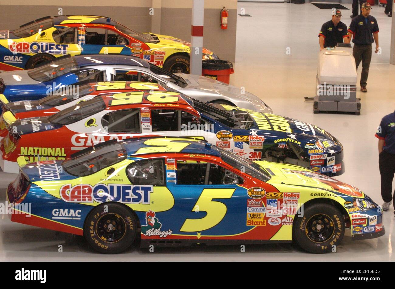 A cleaning crew works around the newly-built race cars of Kyle Busch ...