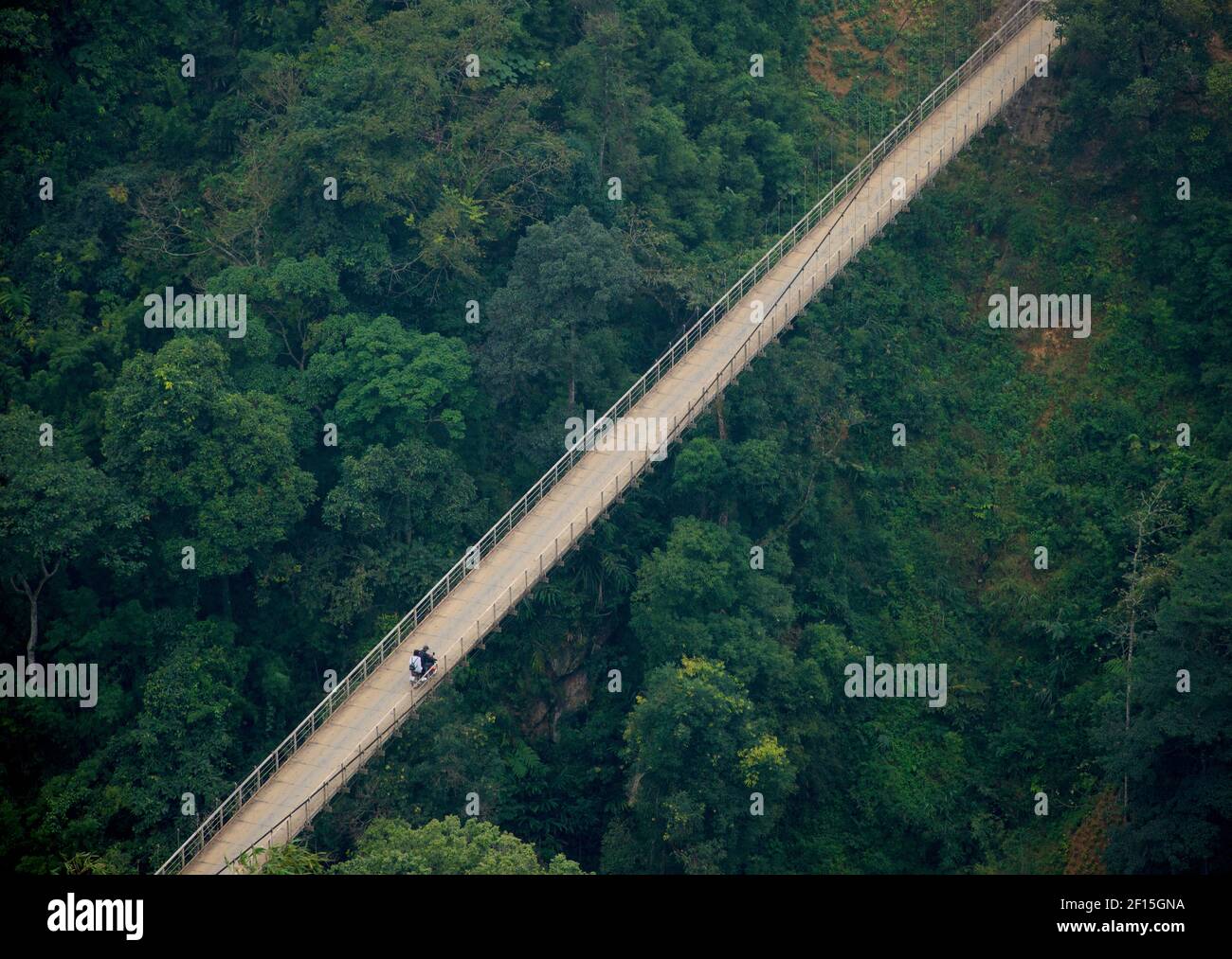 Couple on a motorbike crossing a suspension bridge. Aerial perspective ...