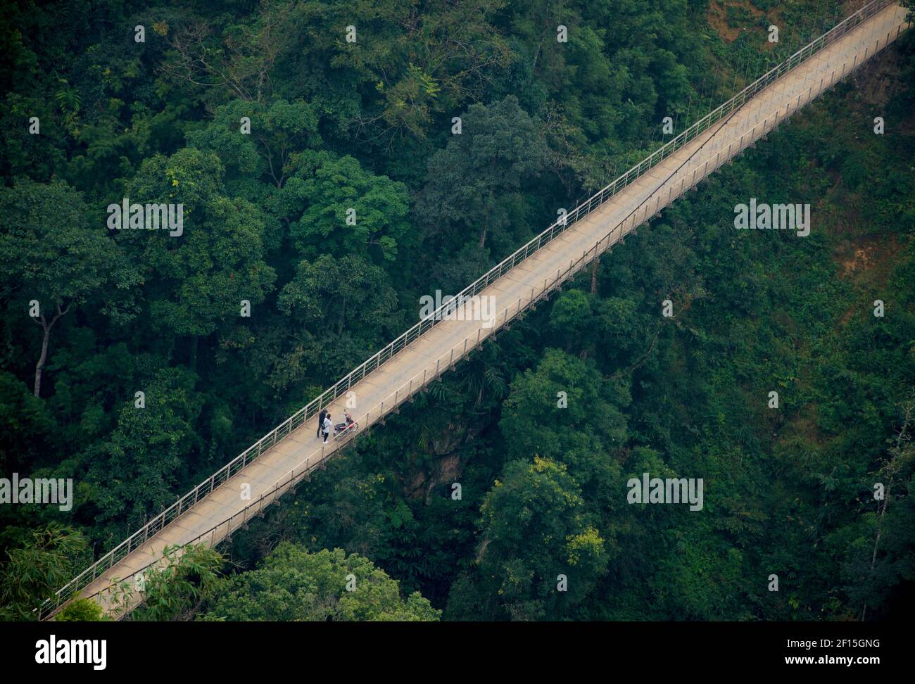Couple on a motorbike crossing a suspension bridge. Aerial perspective ...