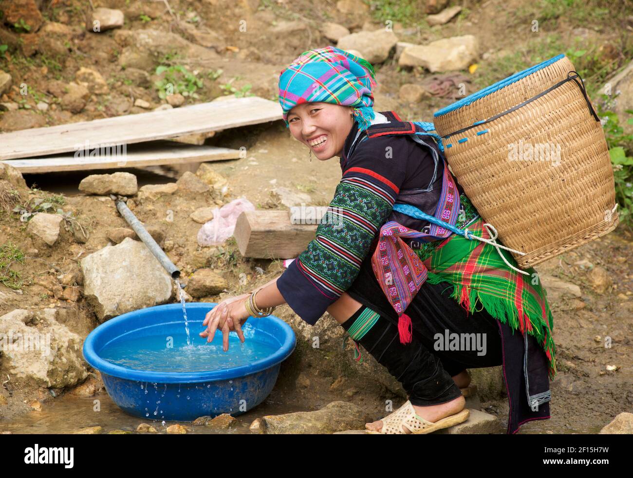 Portrait of a young Hmong woman washing her hands with water from a ...