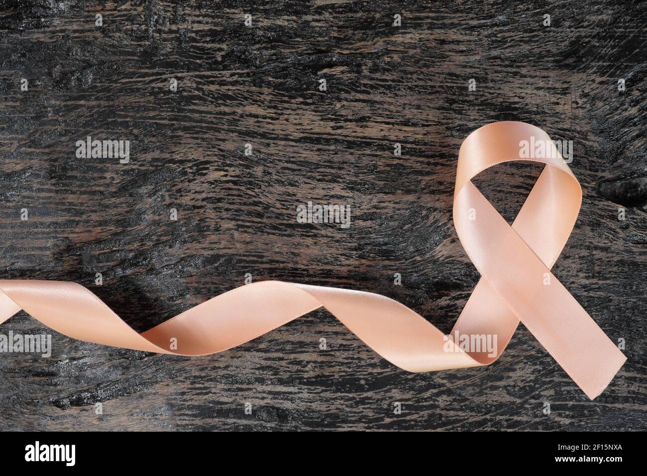 Top view of peach ribbon on dark wood background. Uterine and ...