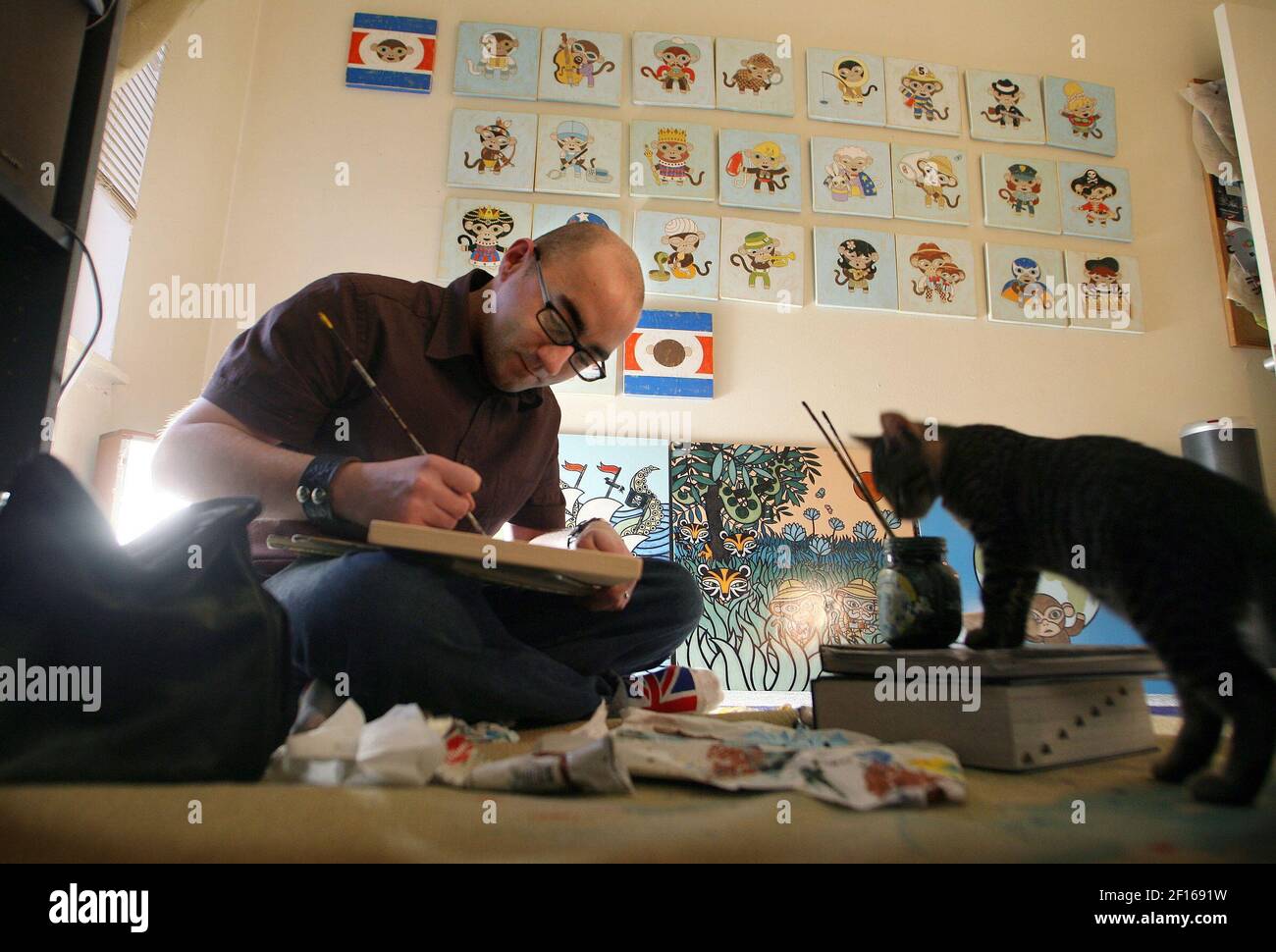 Porter paints in a bedroom while 3-month-old kitty Louie checks the ...