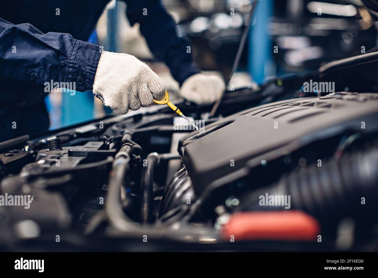 Auto car repair service center. Mechanic checking engine oil level ...