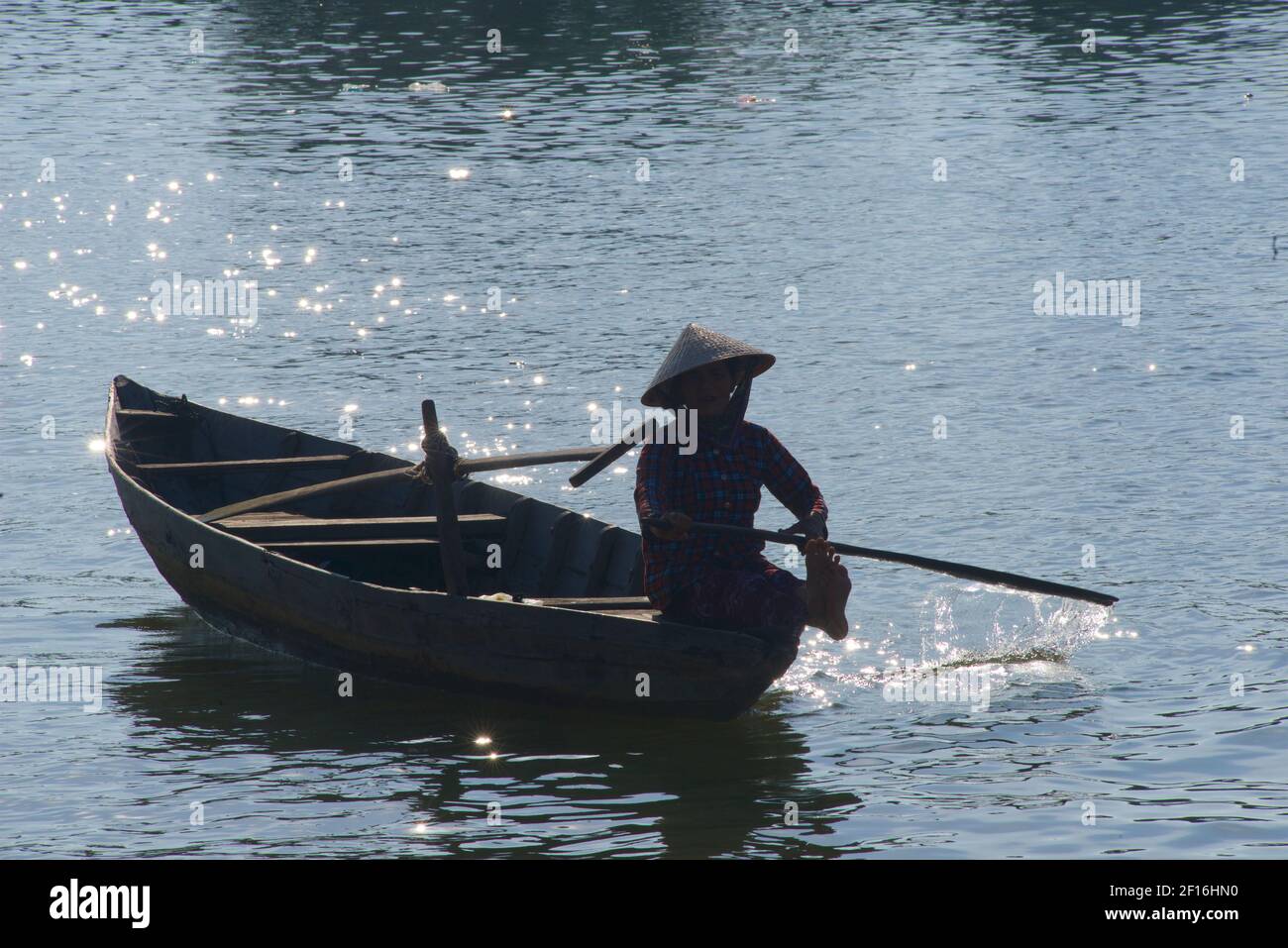 Vietnamese woman in distinctive conical hat in a small boat on the Thu ...